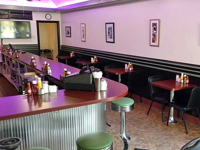 Inside, the purple-tinged lighting and retro green counter stools create that perfect diner atmosphere where comfort food and conversation flow freely.