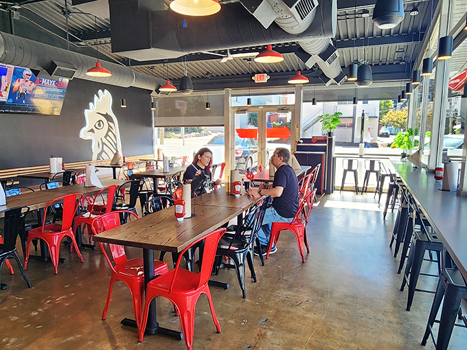 Industrial chic meets Southern comfort, where red chairs and rooster art set the stage for culinary adventure.