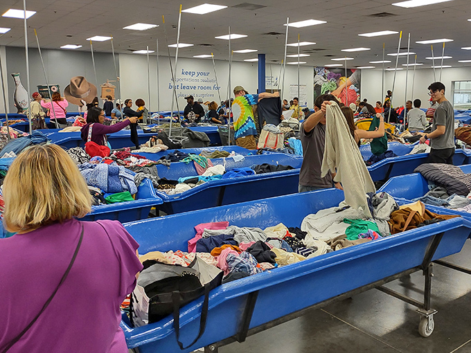 Treasure hunters navigate blue bins like seasoned archaeologists, each dive potentially revealing fashion gold.