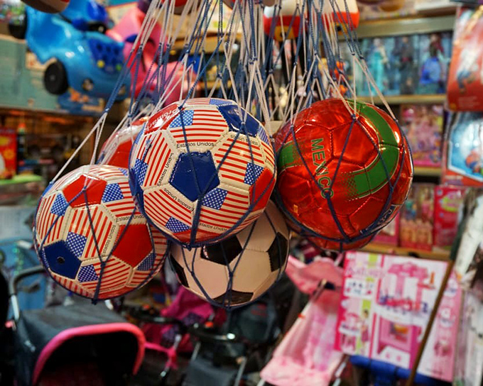 Soccer balls that tell stories of national pride hang like festive ornaments. Each one a potential weekend of family matches and neighborhood bragging rights.