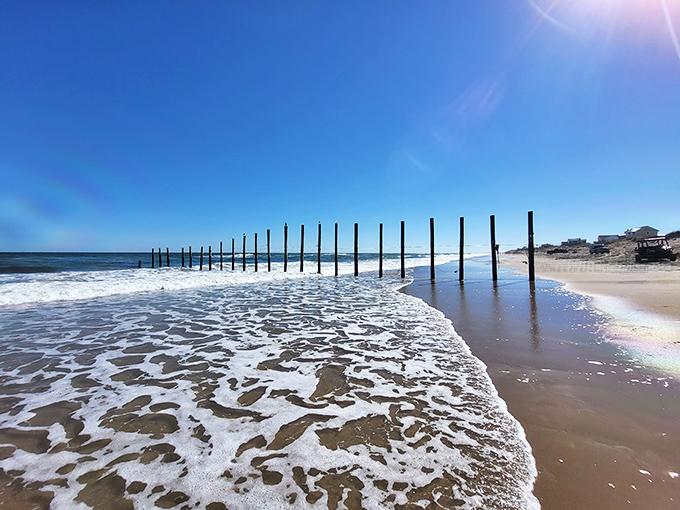 Where ocean meets shore in a frothy handshake. These wooden sentinels have witnessed countless tides, standing guard over pristine sands.