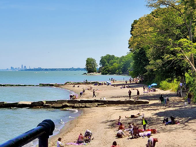 Beach day bingo: sunshine, sand castles, colorful umbrellas, and Cleveland's skyline playing peek-a-boo in the distance. Pure summer perfection.