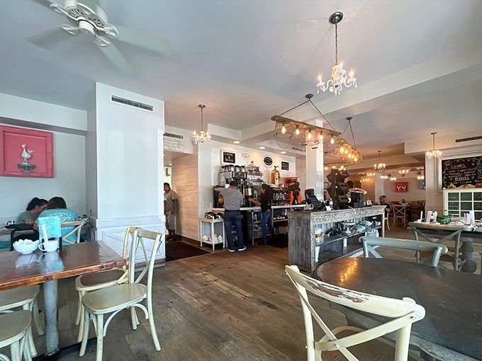 Inside, rustic charm meets modern comfort where chandeliers dance above weathered wood and morning conversations flow freely.