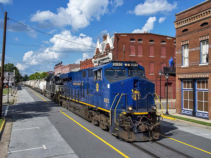 A blue locomotive chugs through downtown Augusta, where affordable living meets small-town charm along historic brick-lined streets.