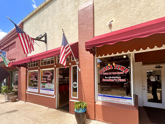 The classic red awning and American flags announce "authentic New York pizza" before you even step inside.