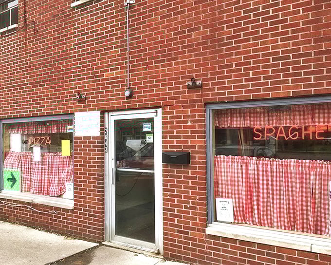 Red checkered curtains whisper promises of authentic Italian comfort waiting just beyond that door.
