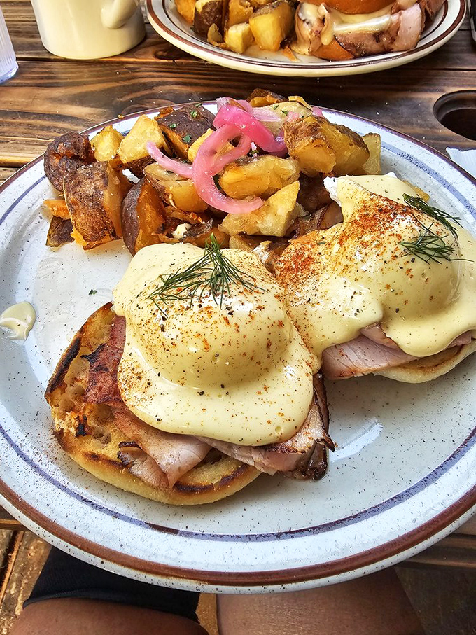 Behold breakfast perfection: poached eggs perched atop English muffins, draped in hollandaise with those game-changing pickled onions adding just the right zing.