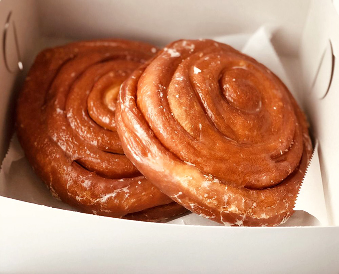 These cinnamon rolls glisten with sweet promise, their spiral design a hypnotic invitation to indulge in morning decadence.
