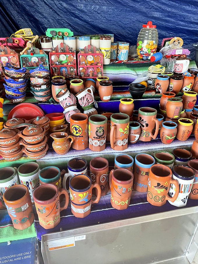 A kaleidoscope of handcrafted pottery transforms a simple table into an artist's palette, each mug telling a different story waiting to be taken home.