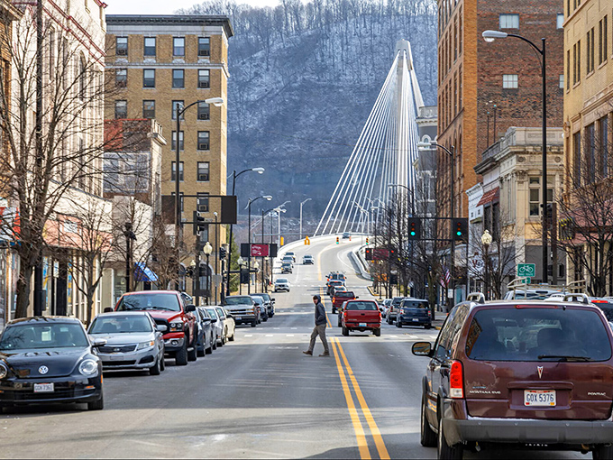 Downtown Portsmouth's streetscape showcases the perfect blend of historic architecture and modern functionality, with the cable-stayed bridge creating a dramatic backdrop against the hills.