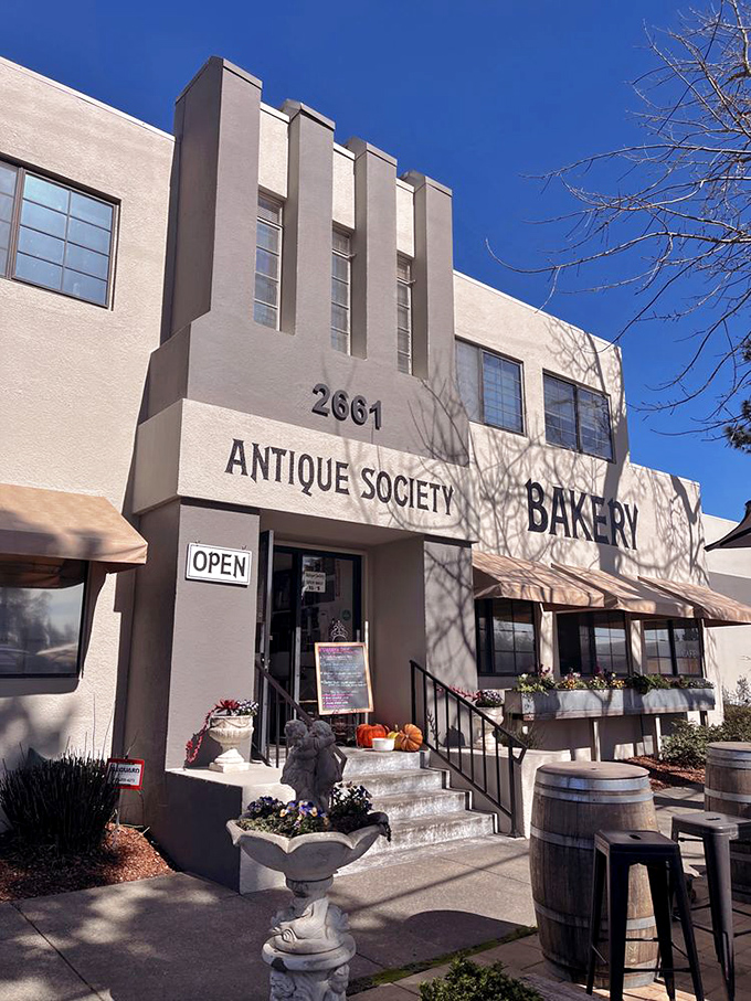 Art Deco architectural details frame the entrance, while rustic wine barrels and garden statuary hint at the eclectic treasures waiting inside.