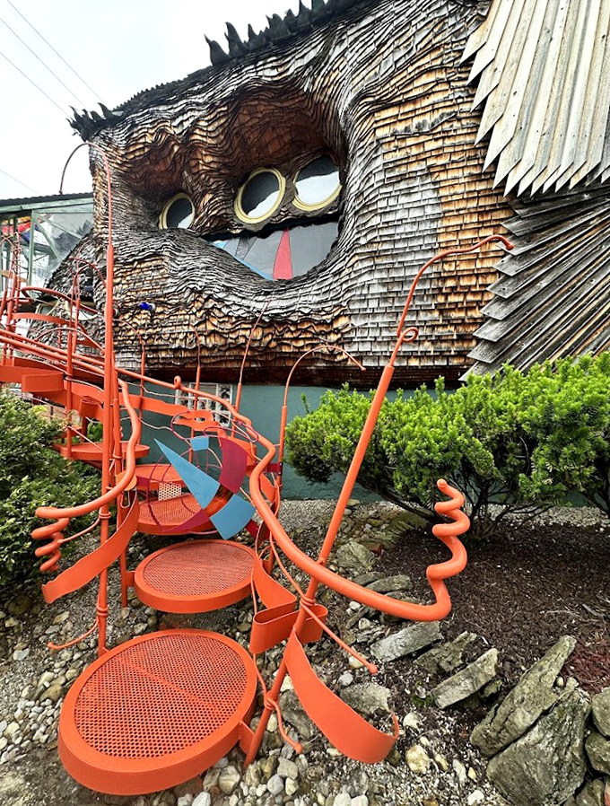 The vibrant orange staircase spirals around the exterior like a psychedelic roller coaster, inviting visitors into this fungal fantasy world.