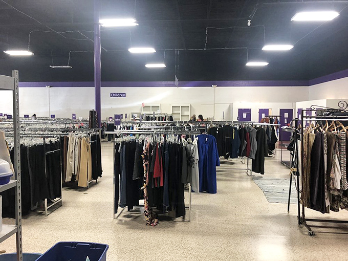 Racks upon racks of carefully organized clothing stretch toward the horizon, a fashionista's dream landscape under purple-trimmed ceilings. 