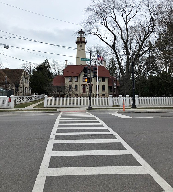 From across Sheridan Road, the lighthouse stands as a dignified sentinel, its white picket fence completing the quintessentially American scene.