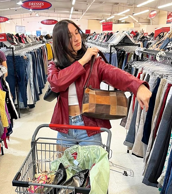 Fashion archaeology in action! This shopper examines a vintage leather jacket that probably costs less than your morning latte.