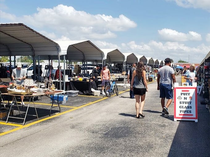 Shoppers stroll through covered stalls where everything from collectibles to crafts awaits, with a sign promising "Stuff N Glass Pipes" for the eclectic browser.