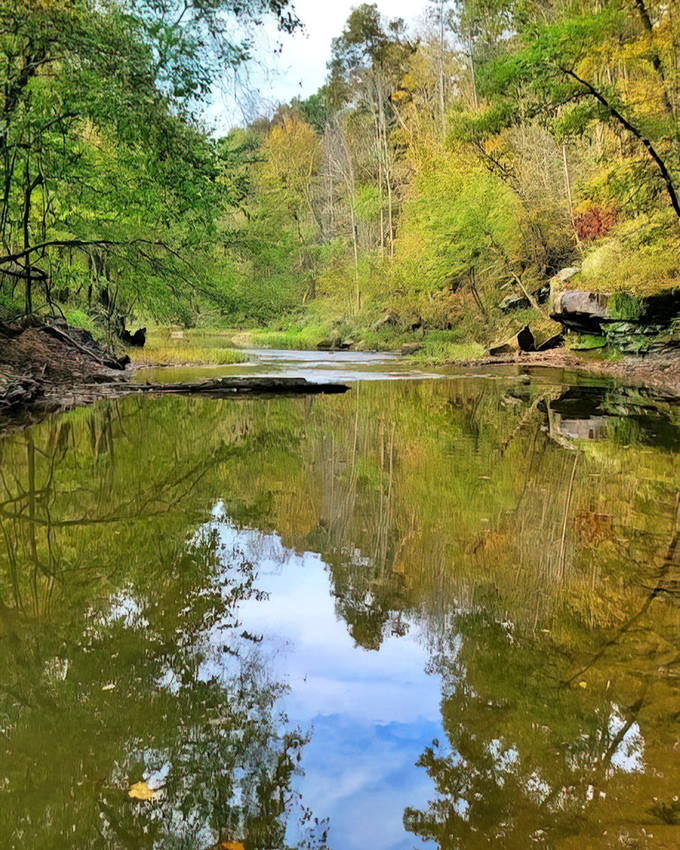 Nature's mirror reflects autumn's palette, creating a double feature of seasonal splendor near the historic crossing.