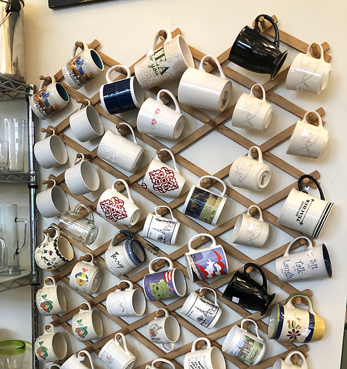 The mug wall: where morning coffee vessels find their second act in an elaborate display that would make Marie Kondo both proud and slightly nervous.