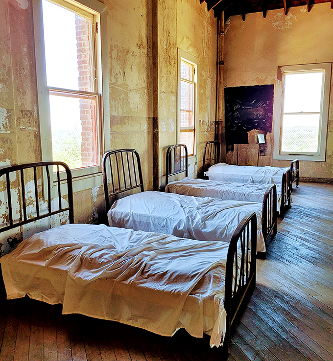 Simple iron beds lined up with military precision remind us that for many young men, this dormitory was both punishment and possibility.