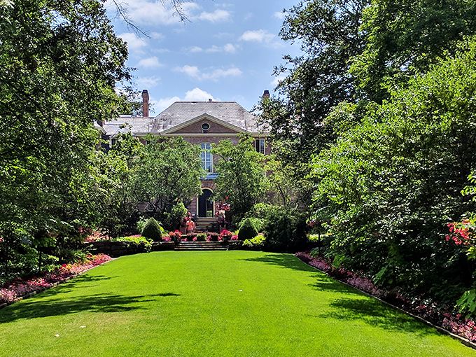 A perfectly manicured lawn creates a green carpet runway to the mansion, framed by vibrant flower beds that practically demand a slow-motion entrance.