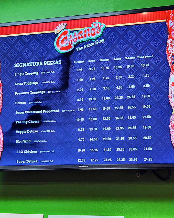 The menu board reveals Cassano's royal lineup, from the humble Single Topping to the majestic Super Deluxe – democracy in pizza form.