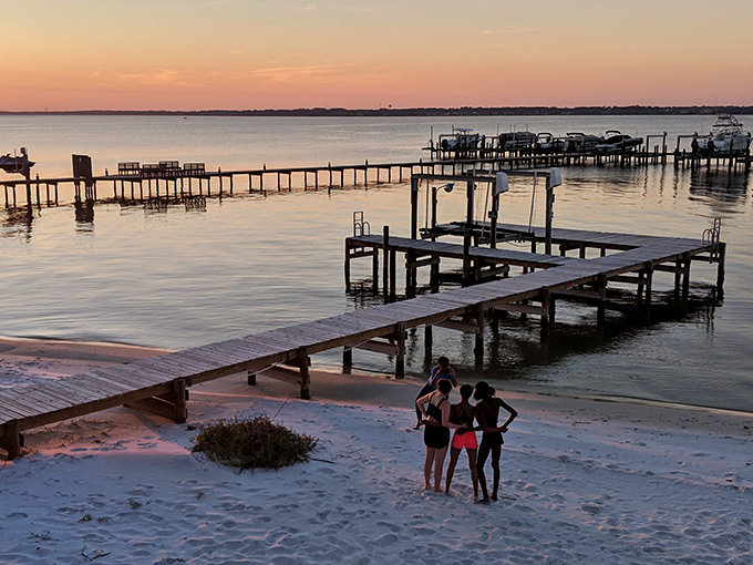 Sunset gatherings: As day surrenders to dusk, friends find their perfect spot on Navarre's sound side, where wooden docks invite conversations that last until stars appear.