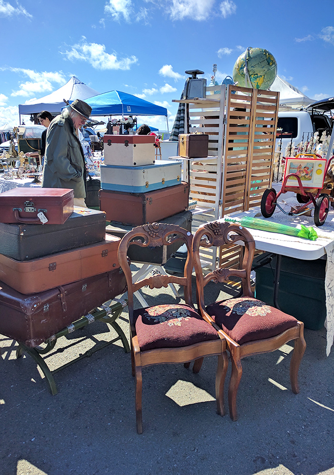 Vintage suitcases stacked high next to elegant wooden chairs. Someone's past becomes another's future!