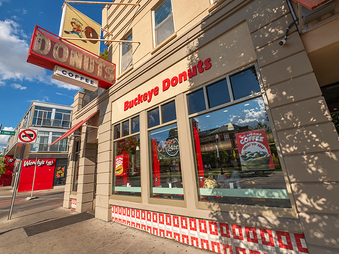 That vintage neon sign has been guiding hungry souls to donut paradise for decades of delicious tradition.