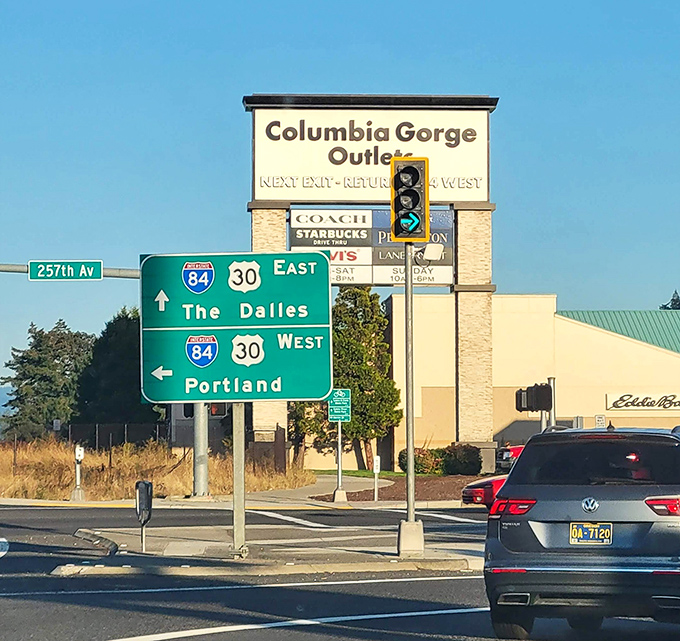 Columbia Gorge Outlets sign stands tall against highway markers, pointing the way to shopping adventures.
