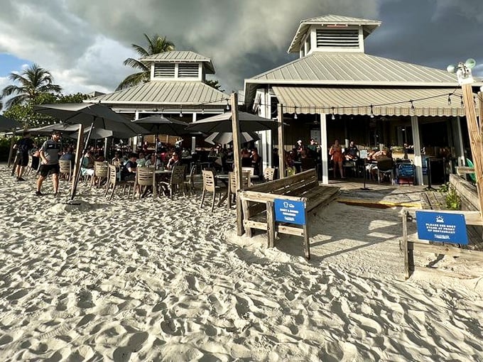 Beach-to-table dining at its finest! The Sandbar's metal roof gleams against dramatic storm clouds, creating a dinner backdrop worthy of a Florida postcard.