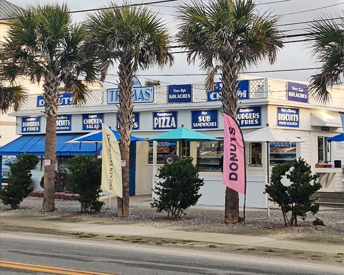 Palm trees and picnic tables create the perfect beach town vibe for enjoying fresh donuts by the shore.