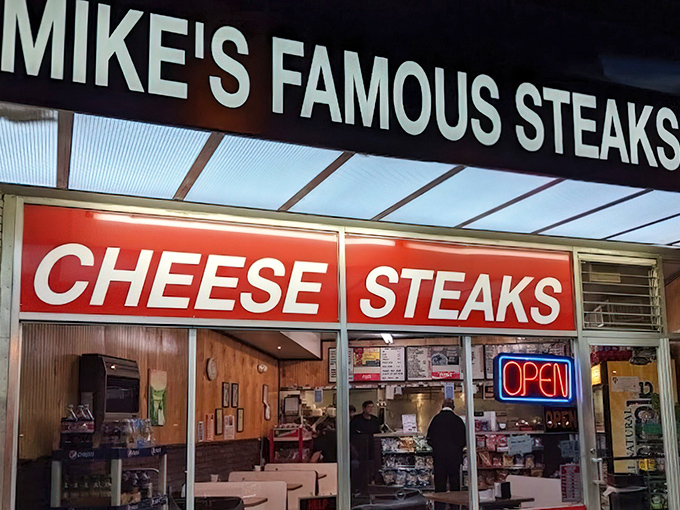 The neon "OPEN" sign at Mike's is like a beacon of hope in a world of disappointing lunches. Your cheesesteak salvation awaits inside.
