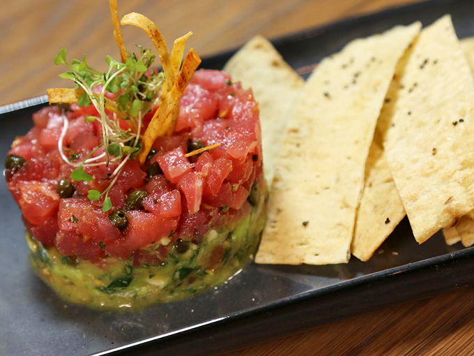 This tuna poke isn't just a dish, it's an edible work of art. Fresh ahi stacked atop creamy avocado with crisp wontons standing by.