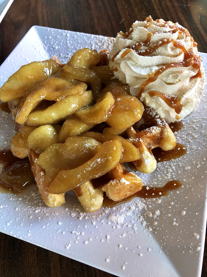 Caramelized apples cascade over a golden waffle, topped with a cloud of whipped cream. Dessert masquerading as breakfast? Count me in.