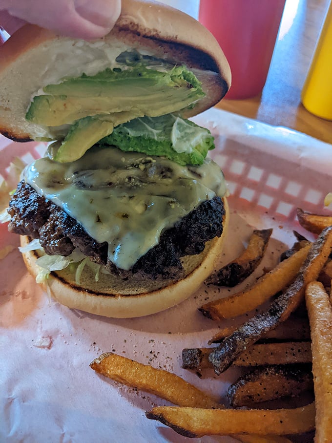 Behold the star attraction: thick slices of buttery avocado crowning a perfectly charred patty. This isn't a burger – it's edible architecture.