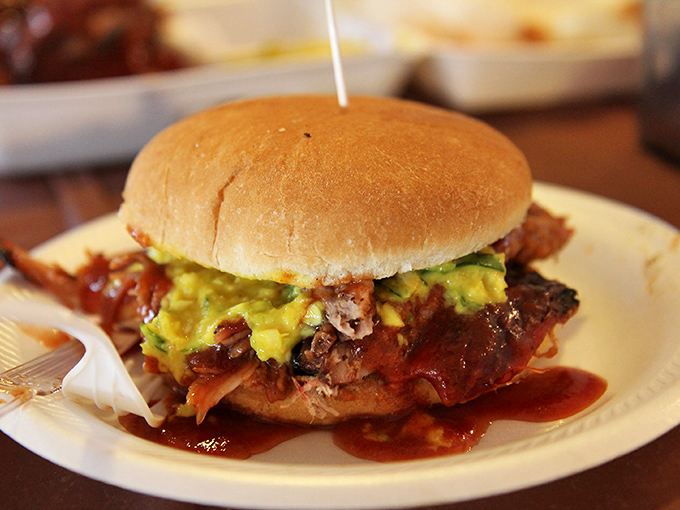 Behold the crown jewel: a perfect marriage of smoky chopped pork, vibrant yellow slaw, and tangy sauce that makes other sandwiches seem like mere practice runs.
