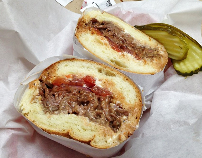Behold the brisket sandwich in all its glory—tender meat cradled in a soft roll with pickle sentinels standing guard.