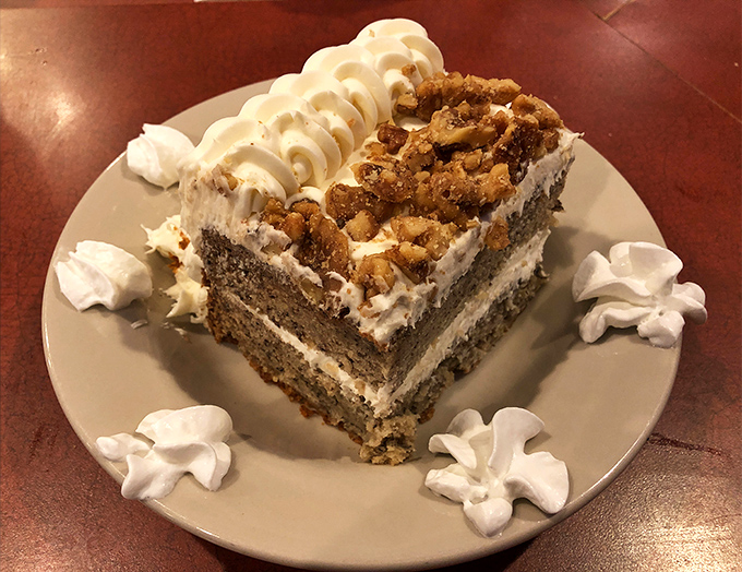 This isn't just banana cake—it's a revelation in dessert form, with layers of moist cake, cream cheese frosting, and what appears to be candied walnuts.