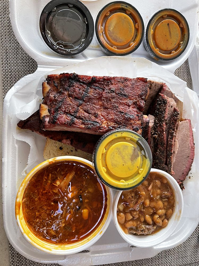Behold the holy trinity of barbecue – ribs with that perfect pink smoke ring, Brunswick stew bubbling with promise, and sides that refuse to be afterthoughts.