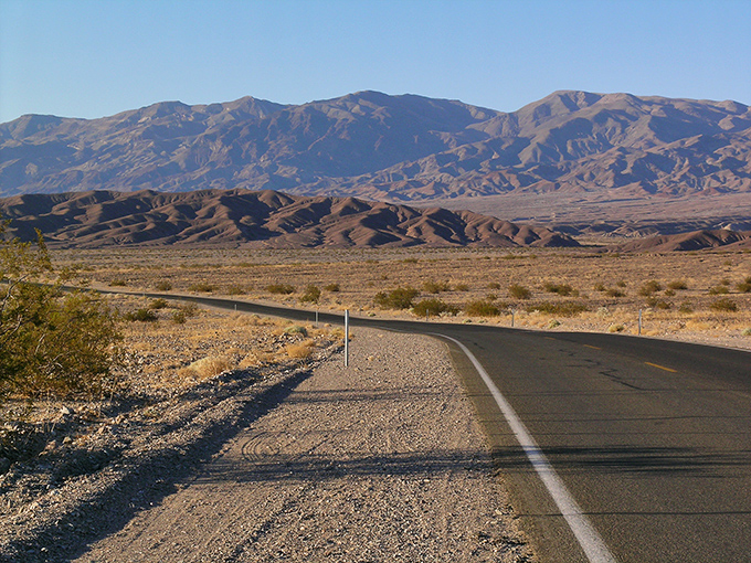 The road stretches toward mountains that look like they're wearing a permanent tan. California's version of the yellow brick road.