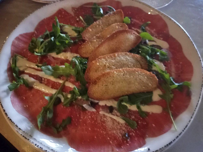 Beef carpaccio that would make an Italian grandmother weep with joy &ndash; paper-thin perfection adorned with arugula, crostini, and just the right touch of olive oil.