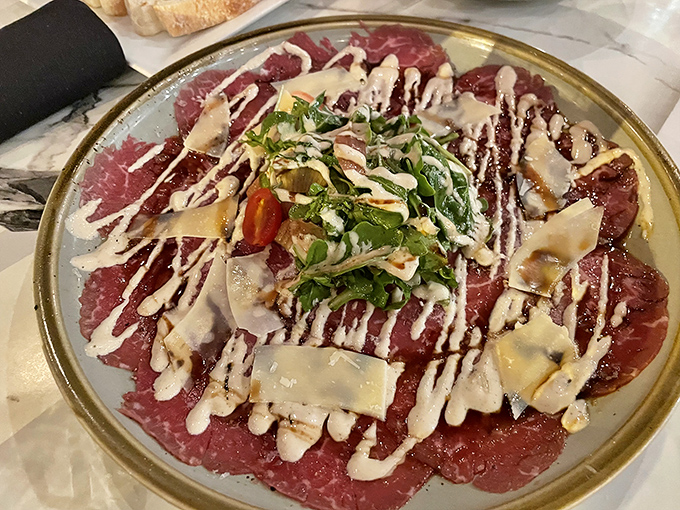 This carpaccio isn't just thinly sliced beef &ndash; it's a canvas where creamy sauce, fresh herbs, and shaved cheese create an edible masterpiece worthy of the Louvre.