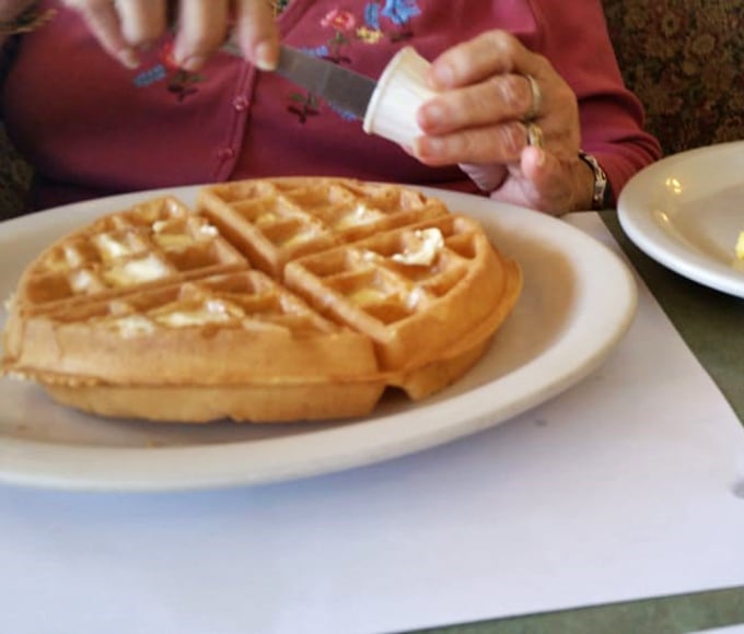 The Belgian waffle arrives like a golden throne for butter and syrup to reign supreme. Crisp exterior, fluffy interior&mdash;this is breakfast engineering at its finest.