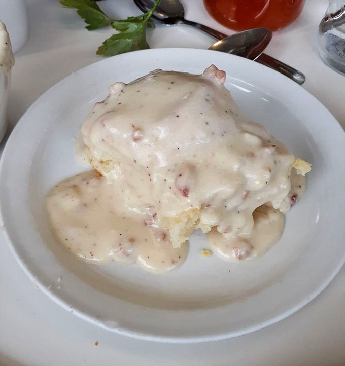 Behold the star attraction: a golden biscuit swimming in creamy, peppery gravy that could make even your grandmother question her recipe.