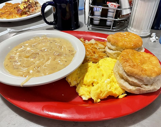 The holy trinity of breakfast perfection: golden biscuits, creamy pepper-flecked gravy, and eggs that would make a chicken proud.