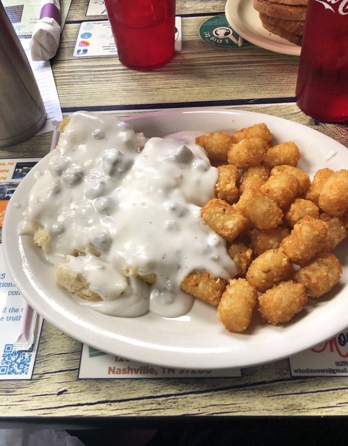 Behold the star attraction: biscuits drowning gloriously in creamy sausage gravy alongside golden tater tots. Poetry on a plate.