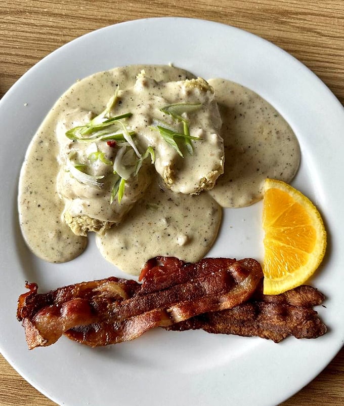 Biscuits swimming in peppery gravy alongside crispy bacon strips—proof that sometimes the simplest pleasures are life's greatest luxuries.