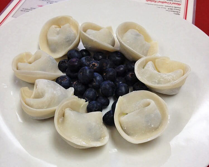 Pierogies arranged like a delicate flower around fresh blueberries. This unexpected sweet variation proves that tradition and innovation can dance beautifully together on the same plate.