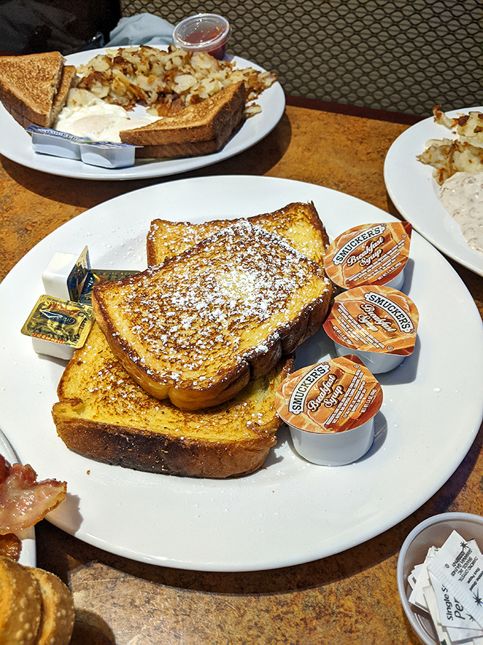 French toast that's achieved golden perfection, dusted with powdered sugar like the first light snow of winter. Smuckers jam packets standing by for backup sweetness.