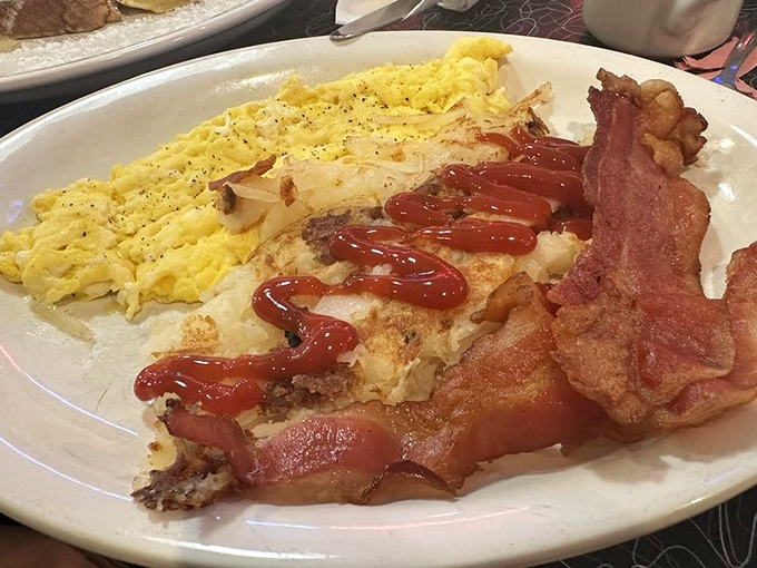 Breakfast architecture at its finest&mdash;scrambled eggs so fluffy they need anchoring, bacon with that perfect crisp-to-chew ratio, and ketchup applied with artistic precision.